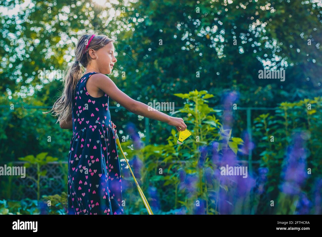 Young caucasian girl or kid is playing badminton game in a lush green ...
