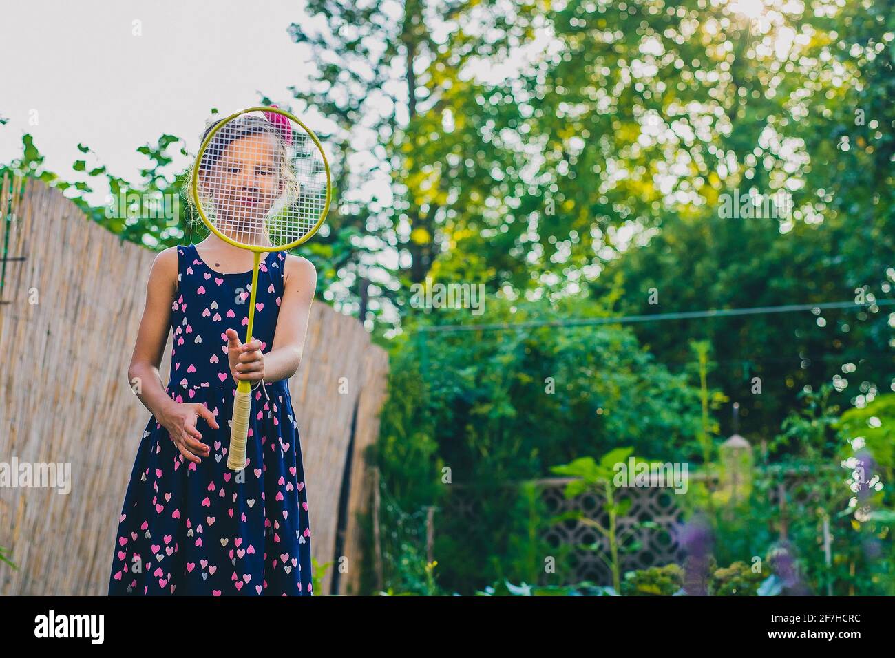 Young caucasian girl or kid is playing badminton game in a lush green ...