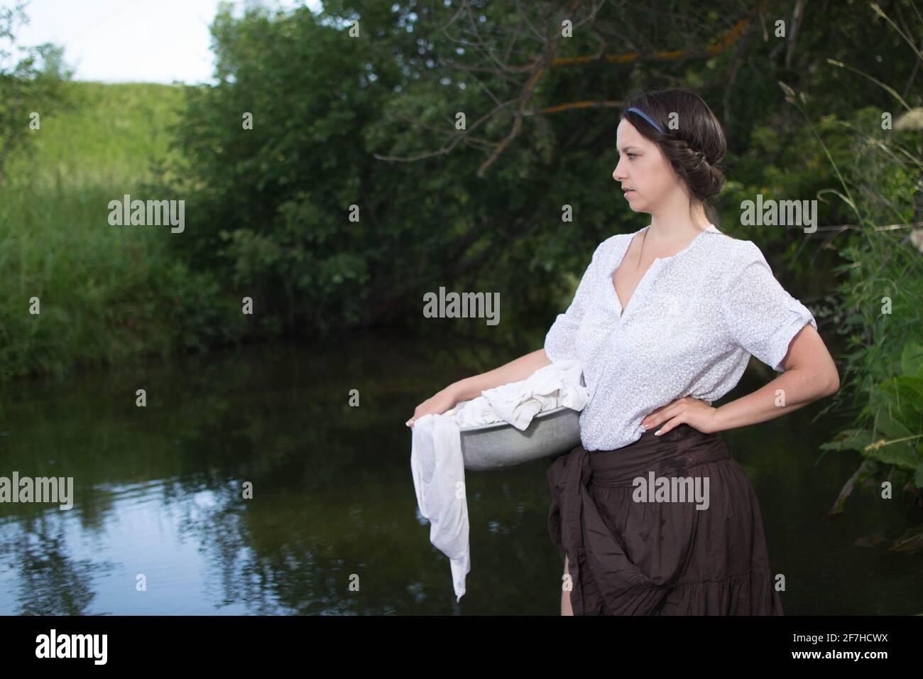 peasant woman washes clothes in the river near the forest Stock Photo ...