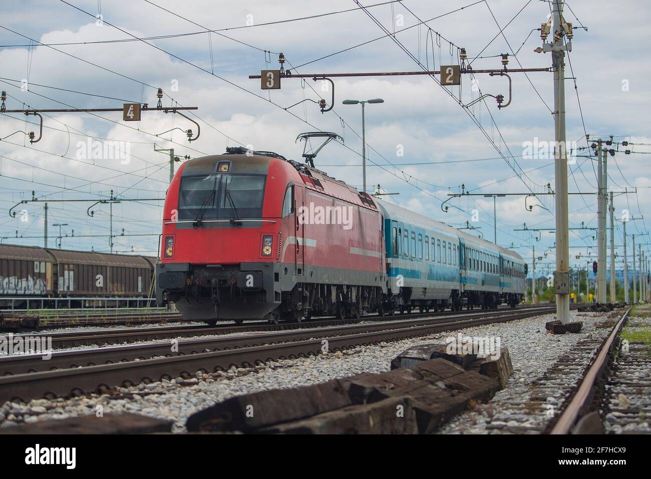 Modern electrical train with red engine on track on a suburban station ...