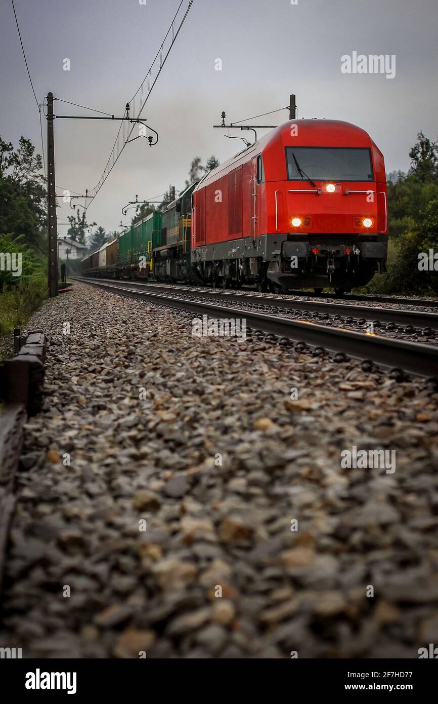 Red diesel locomotive pulling a freight train in rainy weather on a ...