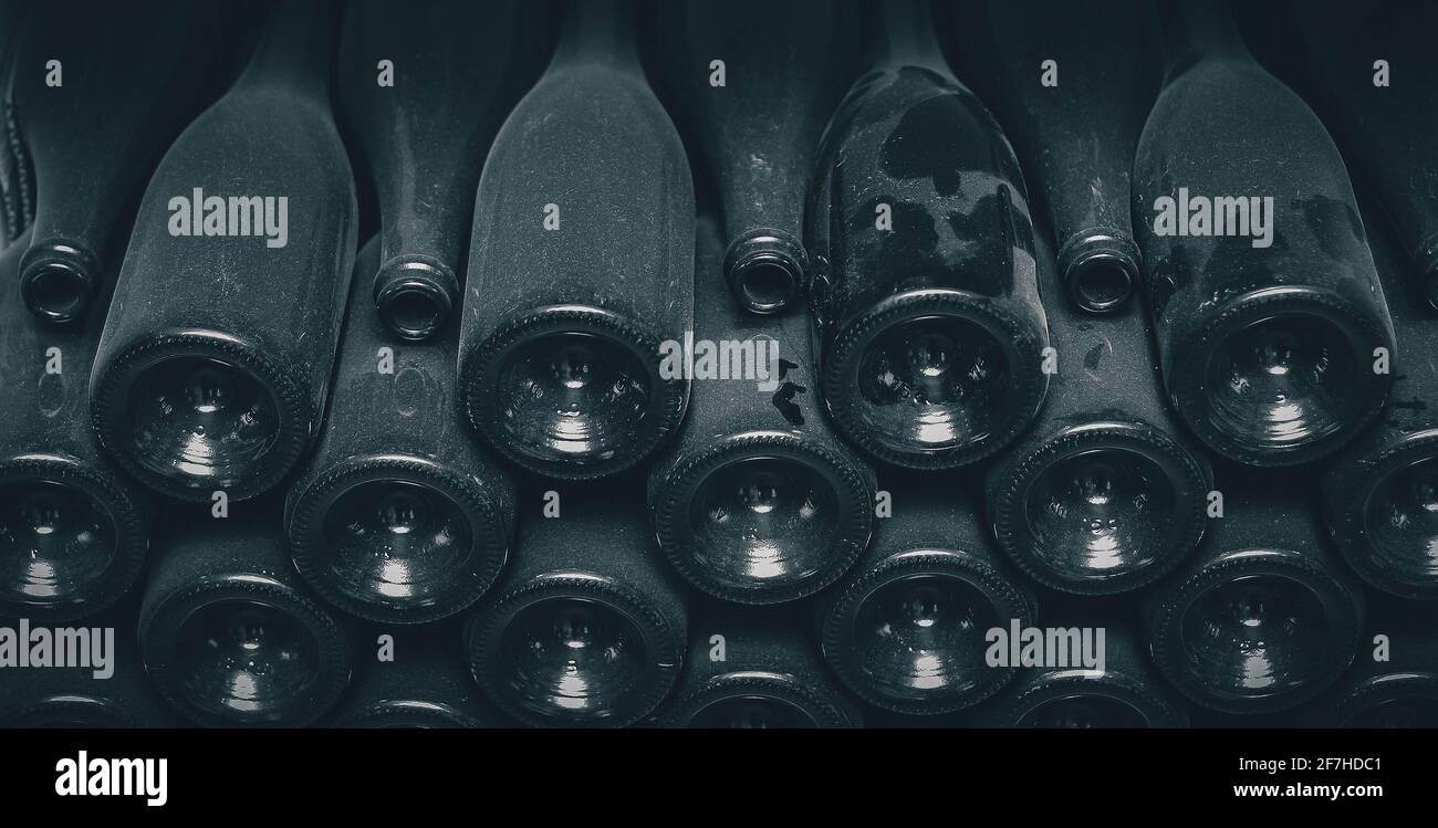 Very dusty old wine bottles stacked on each other in a wine cellar ...