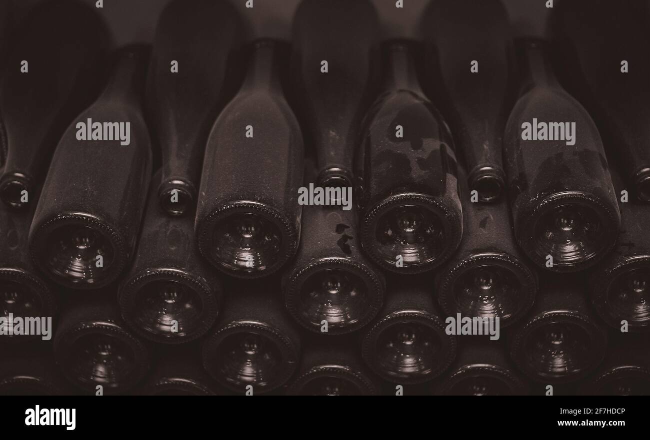 Very dusty old wine bottles stacked on each other in a wine cellar ...