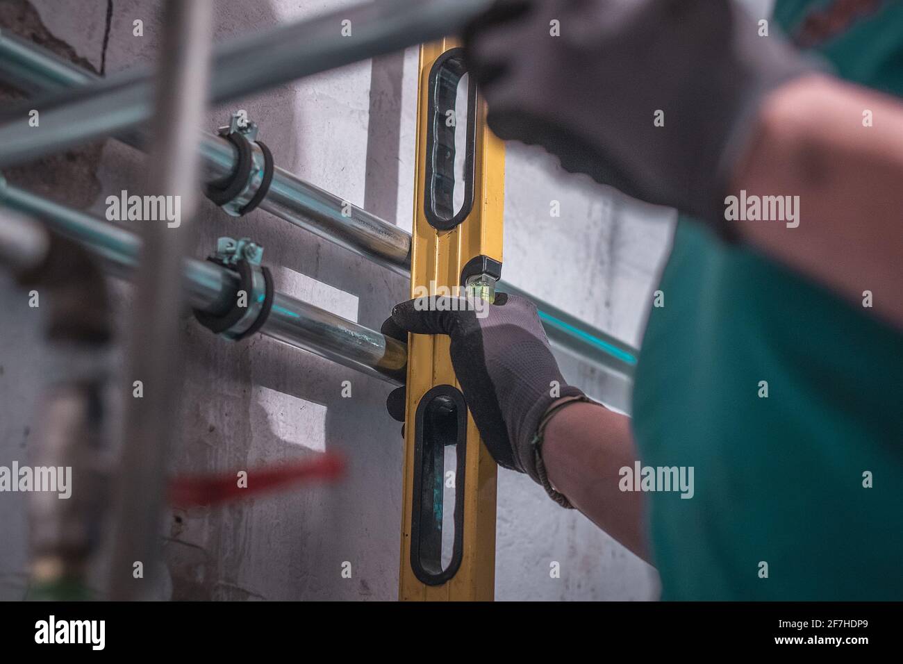Person using water level to align water pipes for plumbing while ...