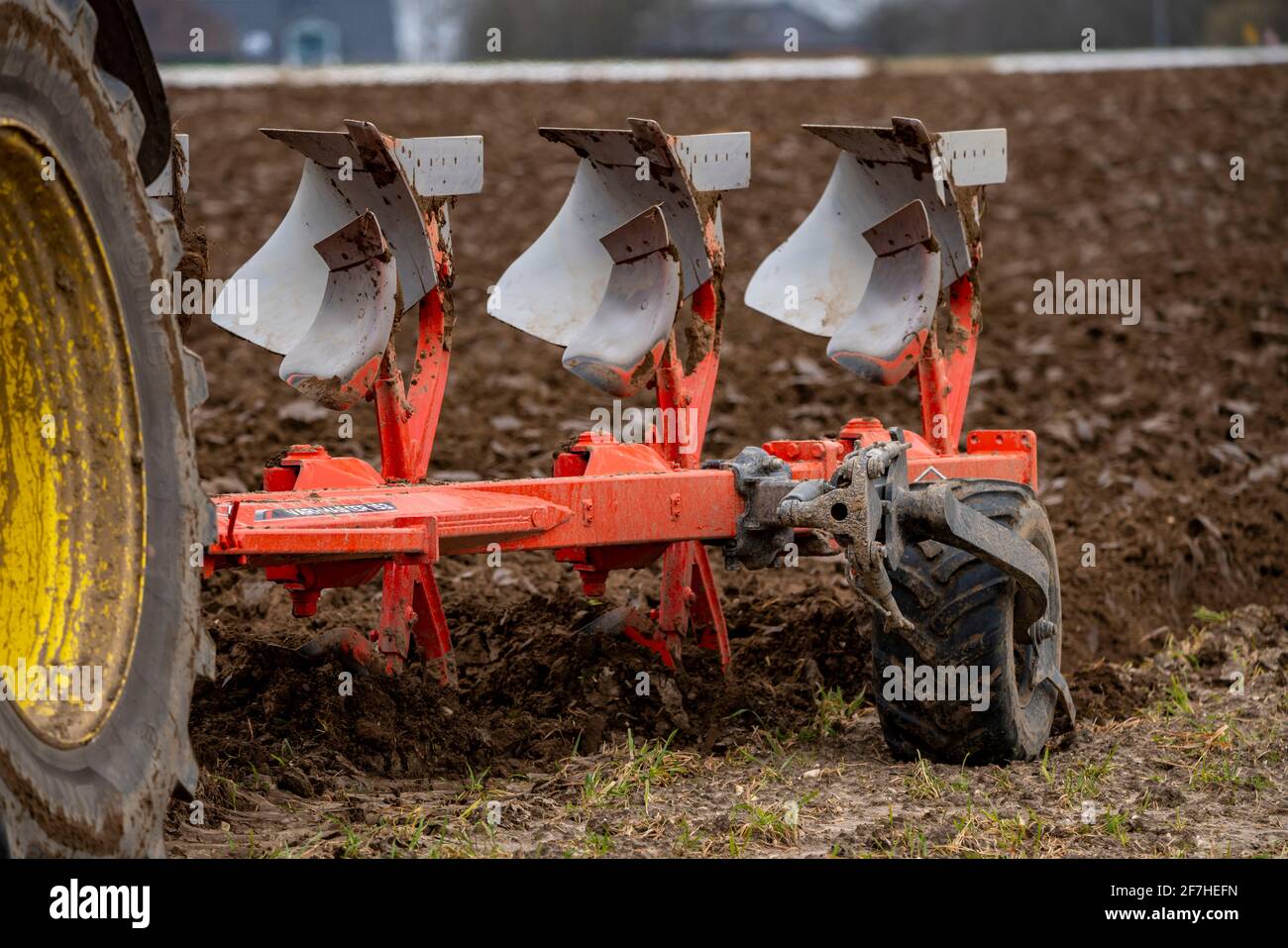 Tractor with a plough preparing the soil of a field for planting ...