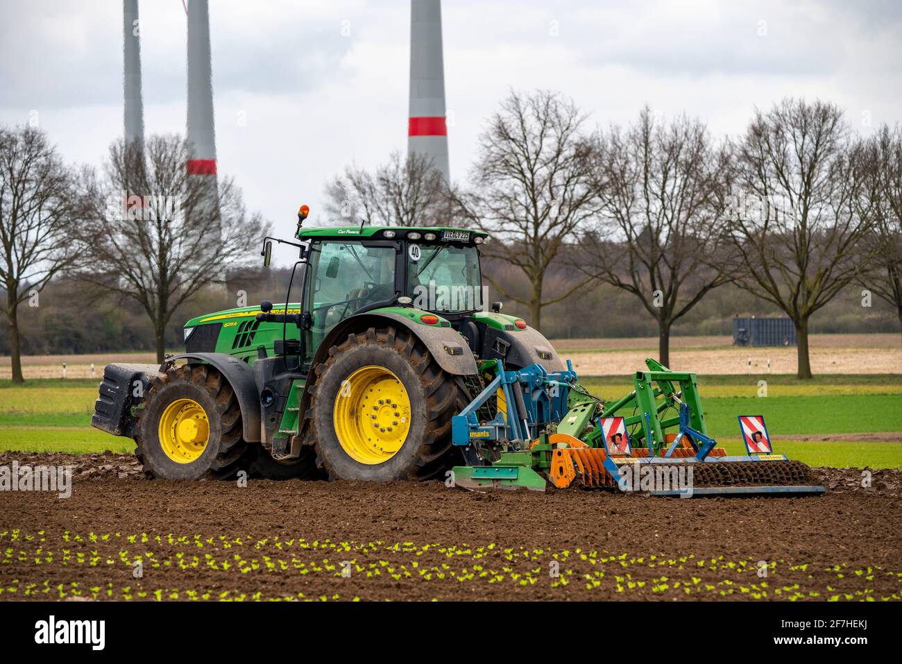Tractor with a power harrow preparing the soil of a field for planting ...