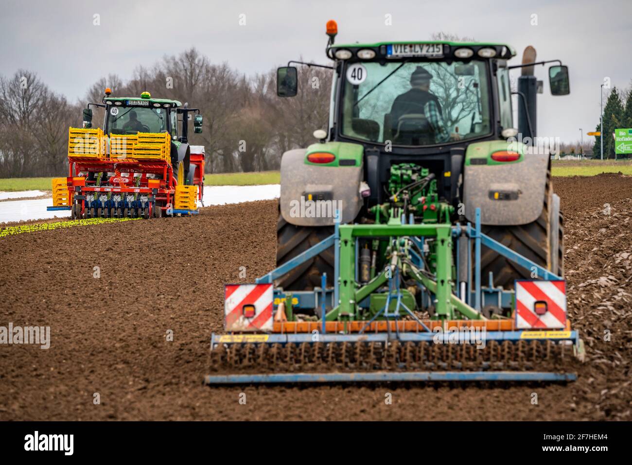 Tractor with a power harrow preparing the soil of a field for planting ...