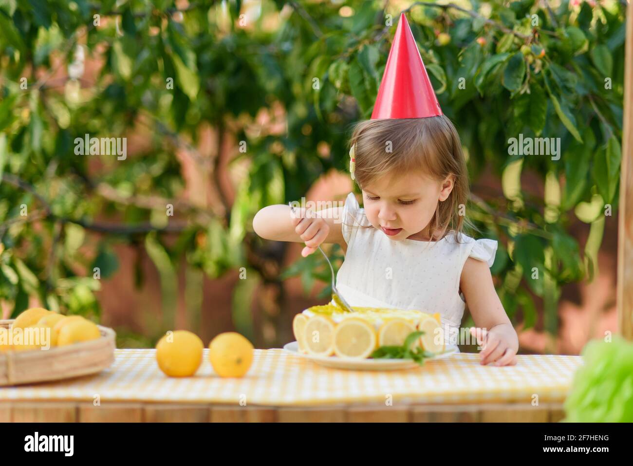 girl eating lemon Birthday cake. Lemonade birthday party at summer park ...