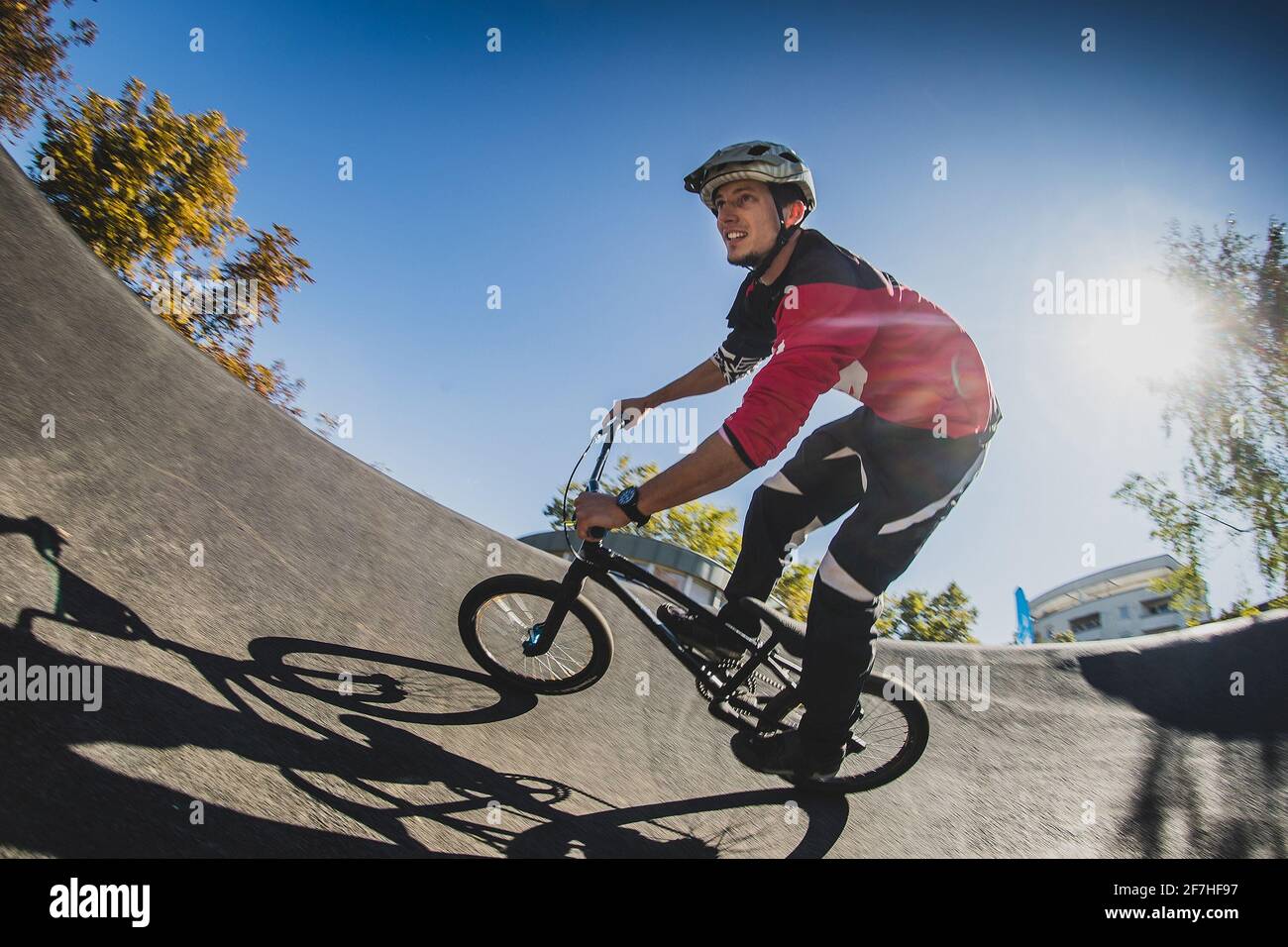 A young male riding a BMX bike through a berm while enjoying a sunny ...