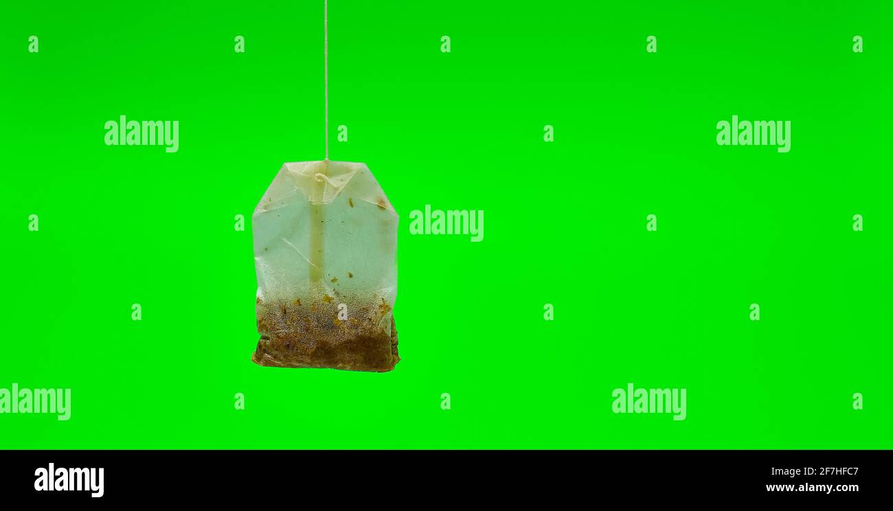 used tea bag on green background Stock Photo - Alamy
