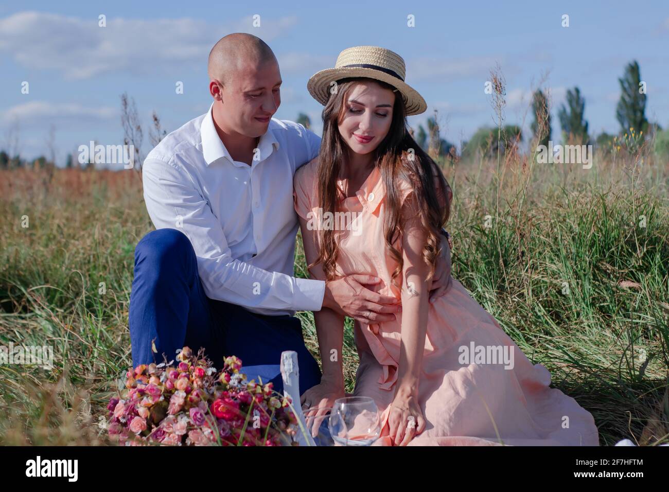 boyfriend and girlfriend on a romantic date on a picnic. brunette and bald man in the field ...