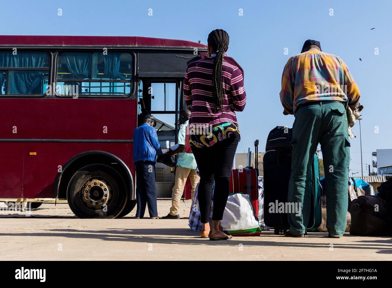 People waiting with luggage to embark on a bus from Dakar to Ziguinchor ...