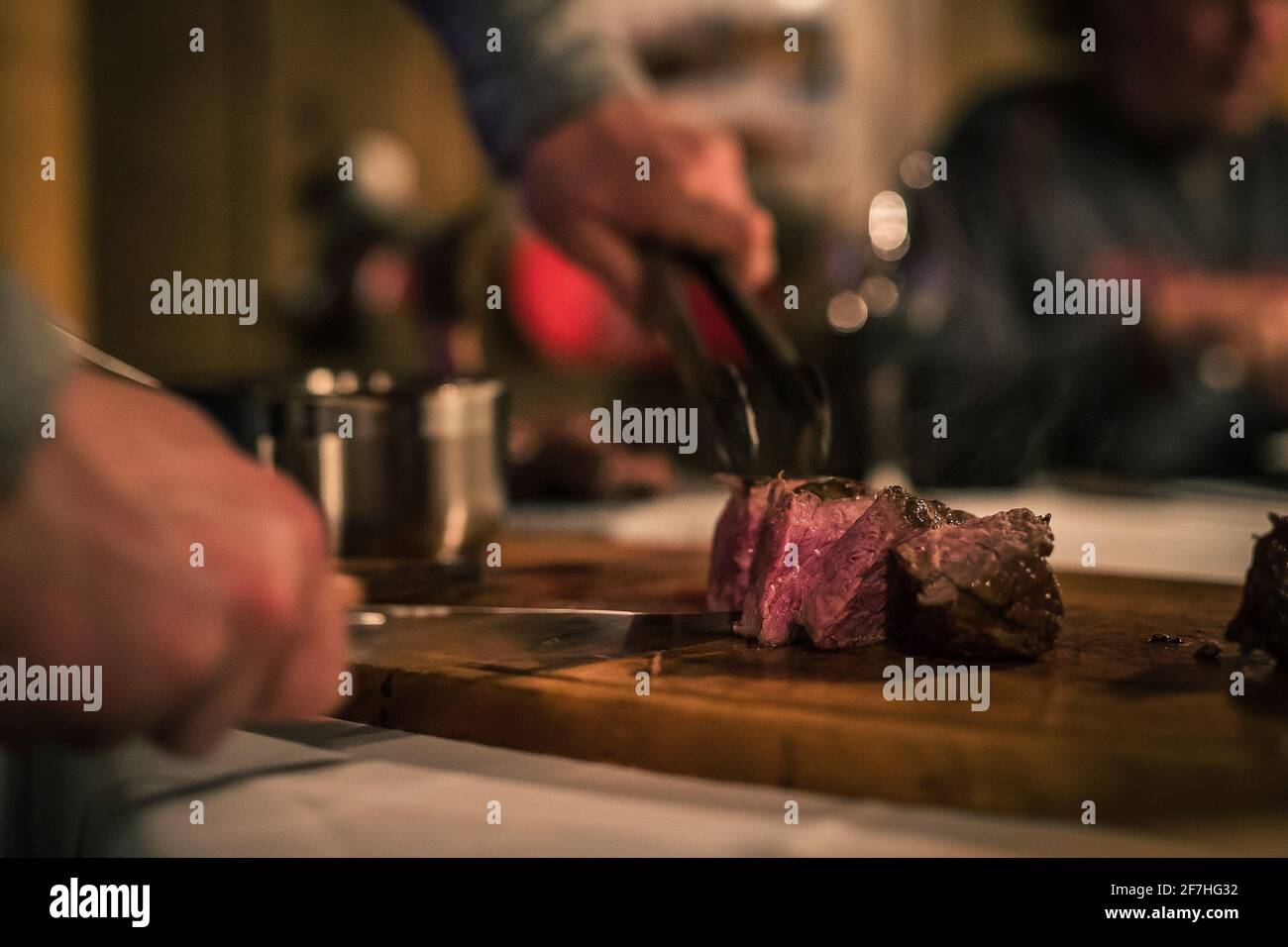 A medium rare fillet steak is being cut on a wooden board on a ...