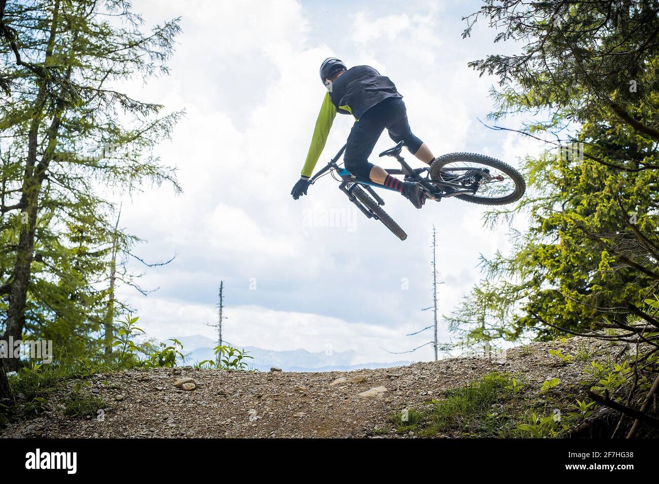 Rear shot of a mountainbiker jumping over a dirt jump in a bike park ...