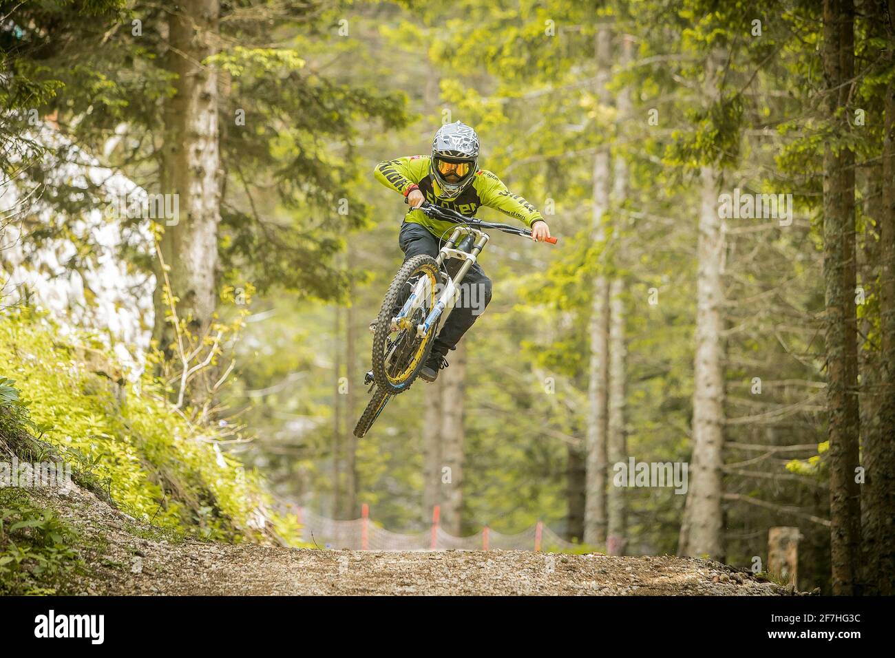 Frontal shot of a young mountainbiker jumping over a dirt jump in a ...
