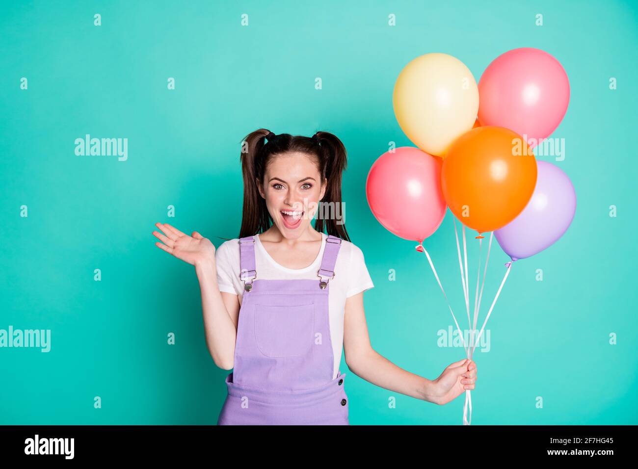 Photo of lovely young girl hold balloons waving palm open mouth wear ...