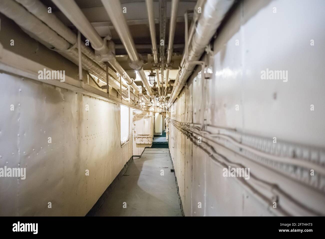 Old metal hallway or tunnel inside of an old warship. Visible piping ...