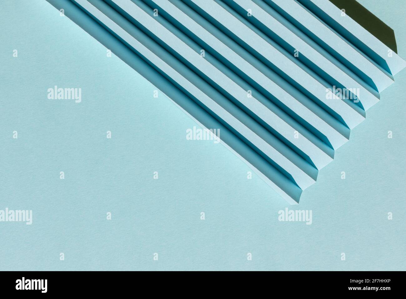 Abstract light blue colored paper texture. Folded paper with harsh sun ...