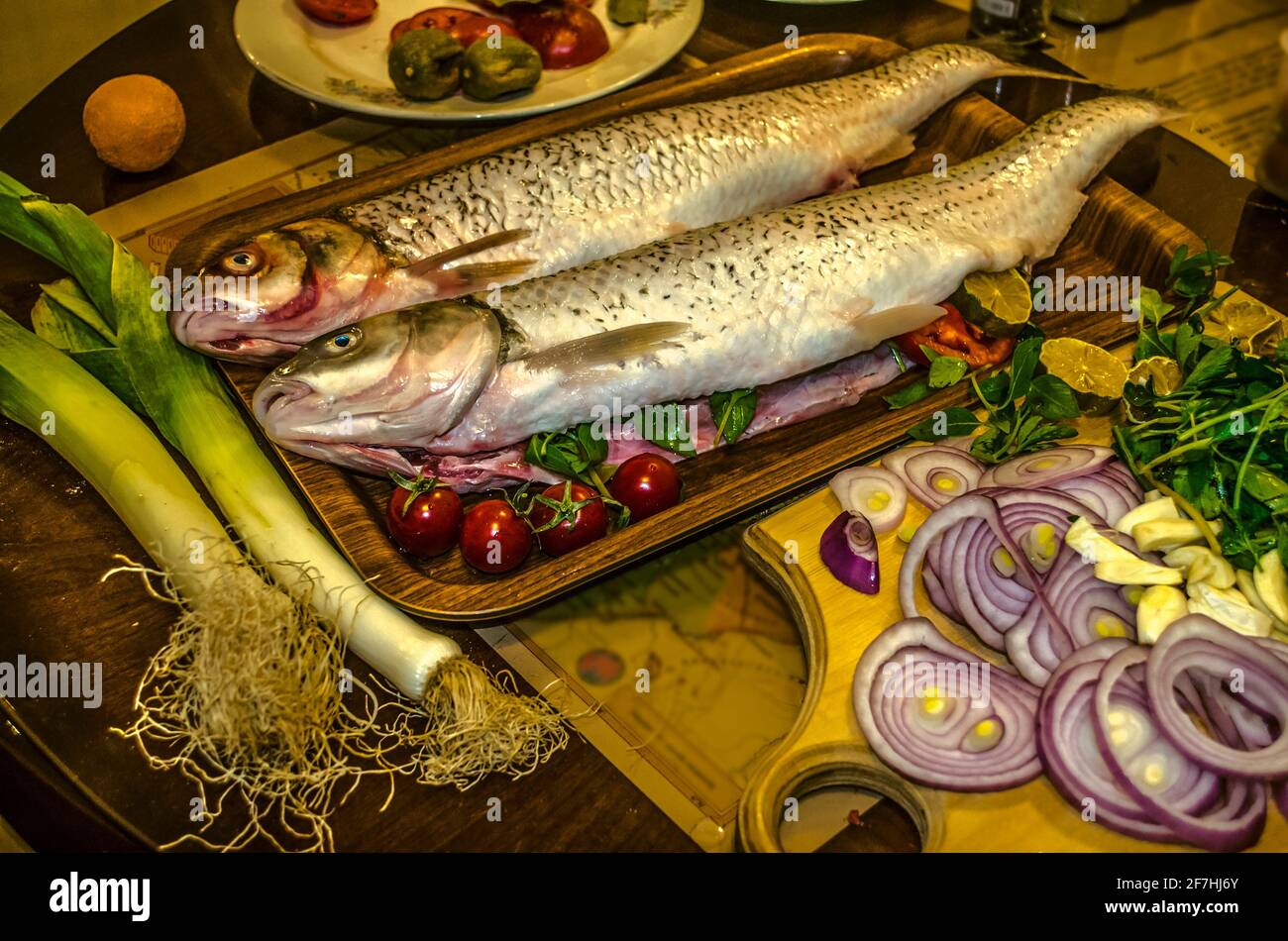 Two peeled pollock fish, stuffed with herbs,lemon wedges with spices on ...