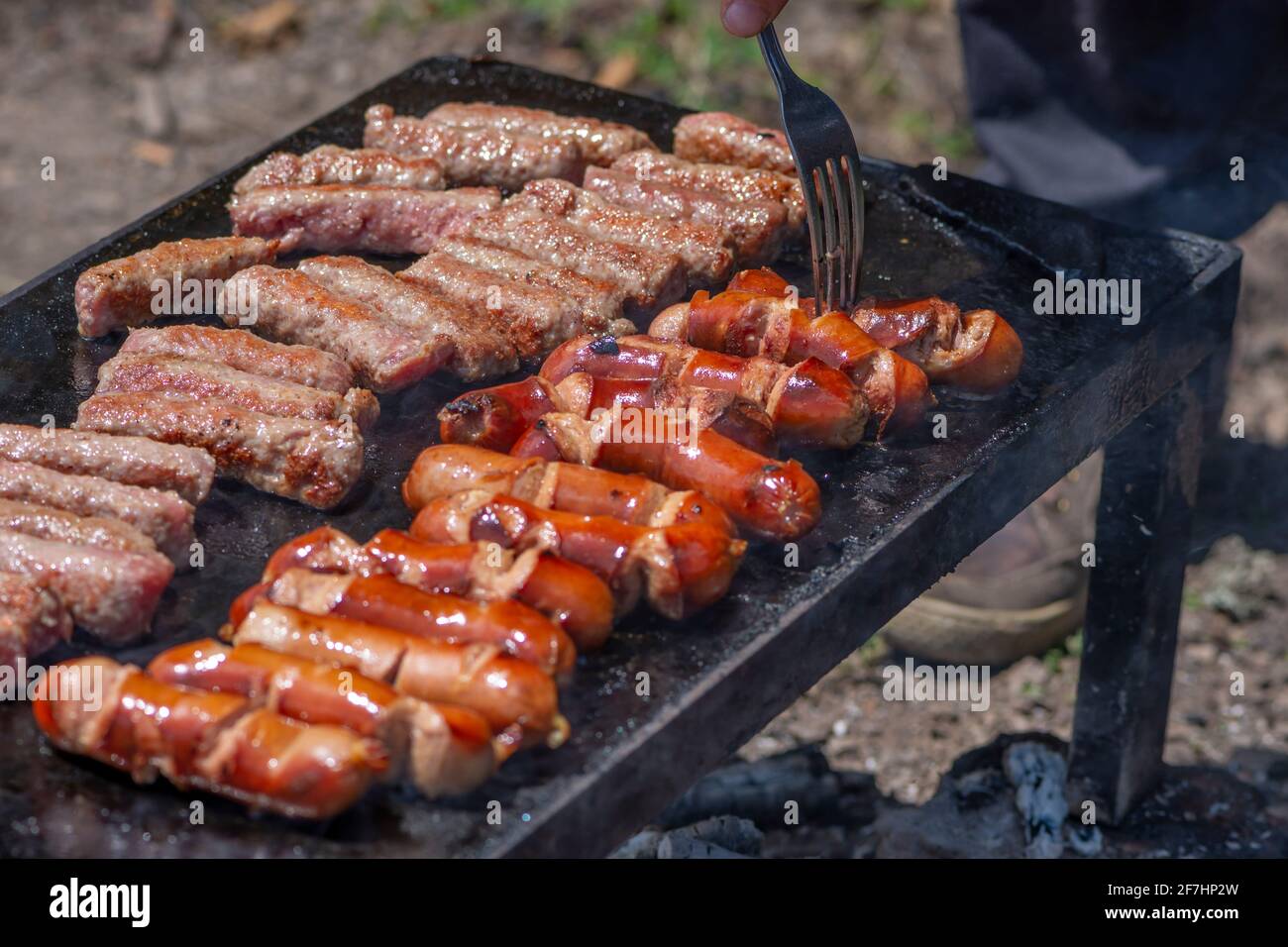 Male hand turning delicious grilled meat by fork Stock Photo - Alamy
