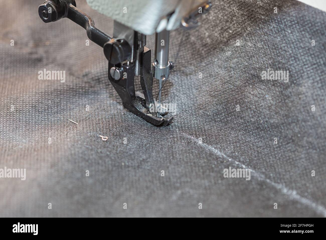 Sewing machine foot and needle close-up makes a stitch on the fabric ...