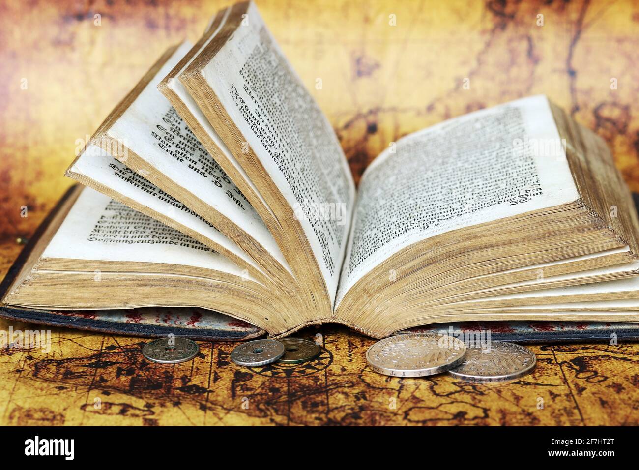 Old silver coins from 1902 and an antique book from 1763 on a world map ...