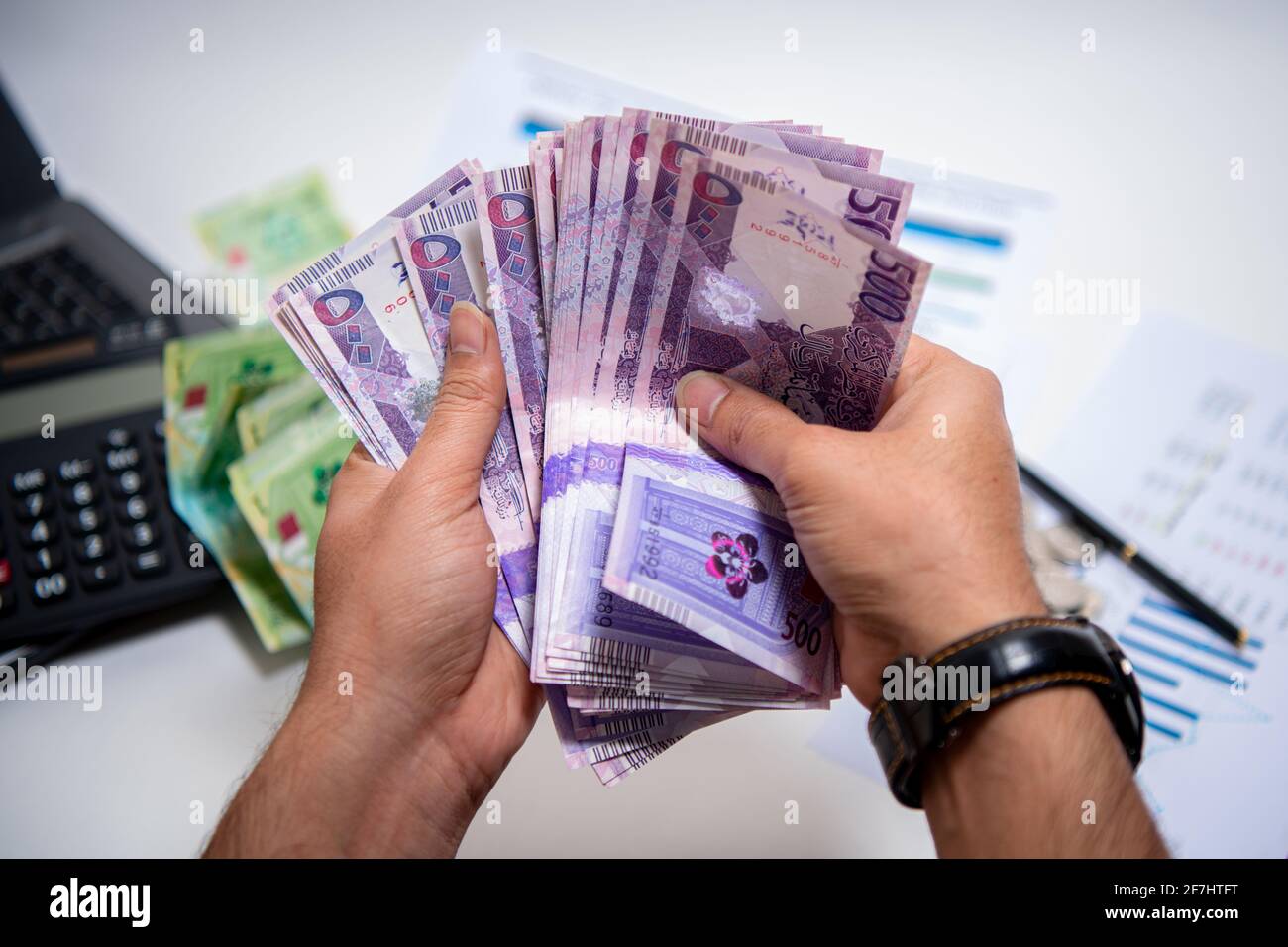 Men's hands holding and Counting Qatari Bank notes. 500 Rial new notes ...