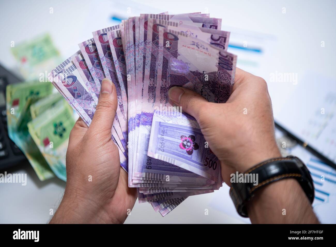 Men's hands holding and Counting Qatari Bank notes. 500 Rial new notes ...