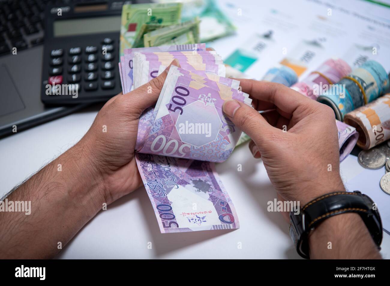 Men's hands holding and Counting Qatari Bank notes. 500 Rial new notes ...