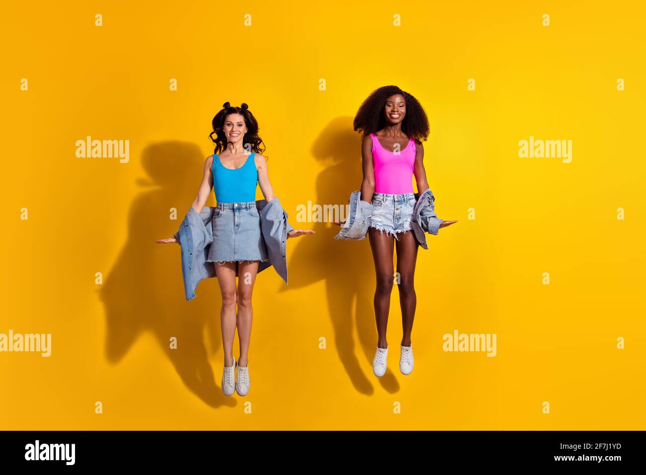 Photo of two adorable ladies jump wear jeans shorts skirt jacket ...