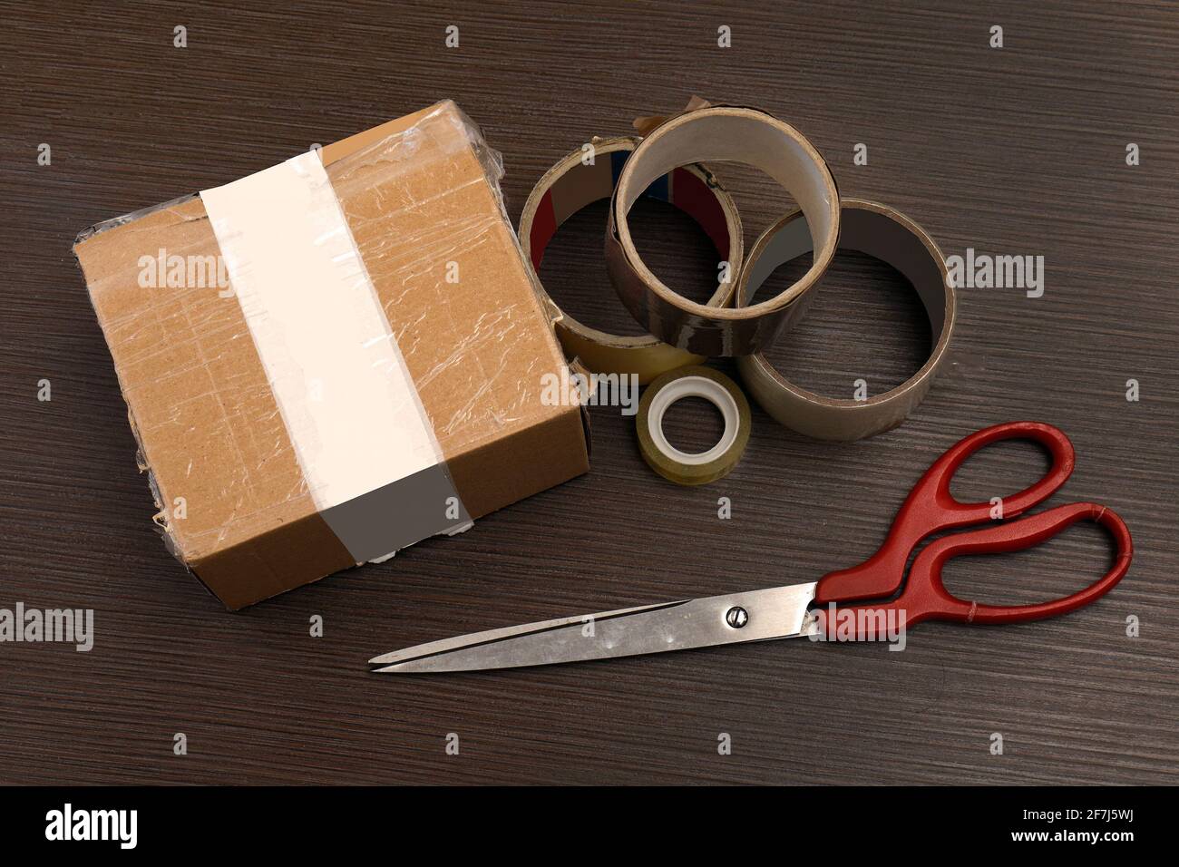 Closed cardboard box duct tape and scissors on table inside ...