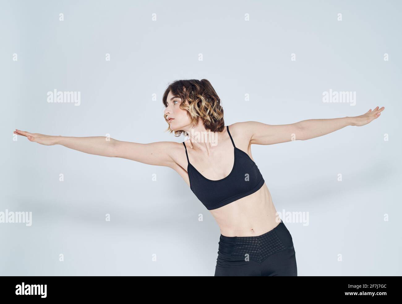 Woman spreads her arms to the sides on a light background sportswear ...