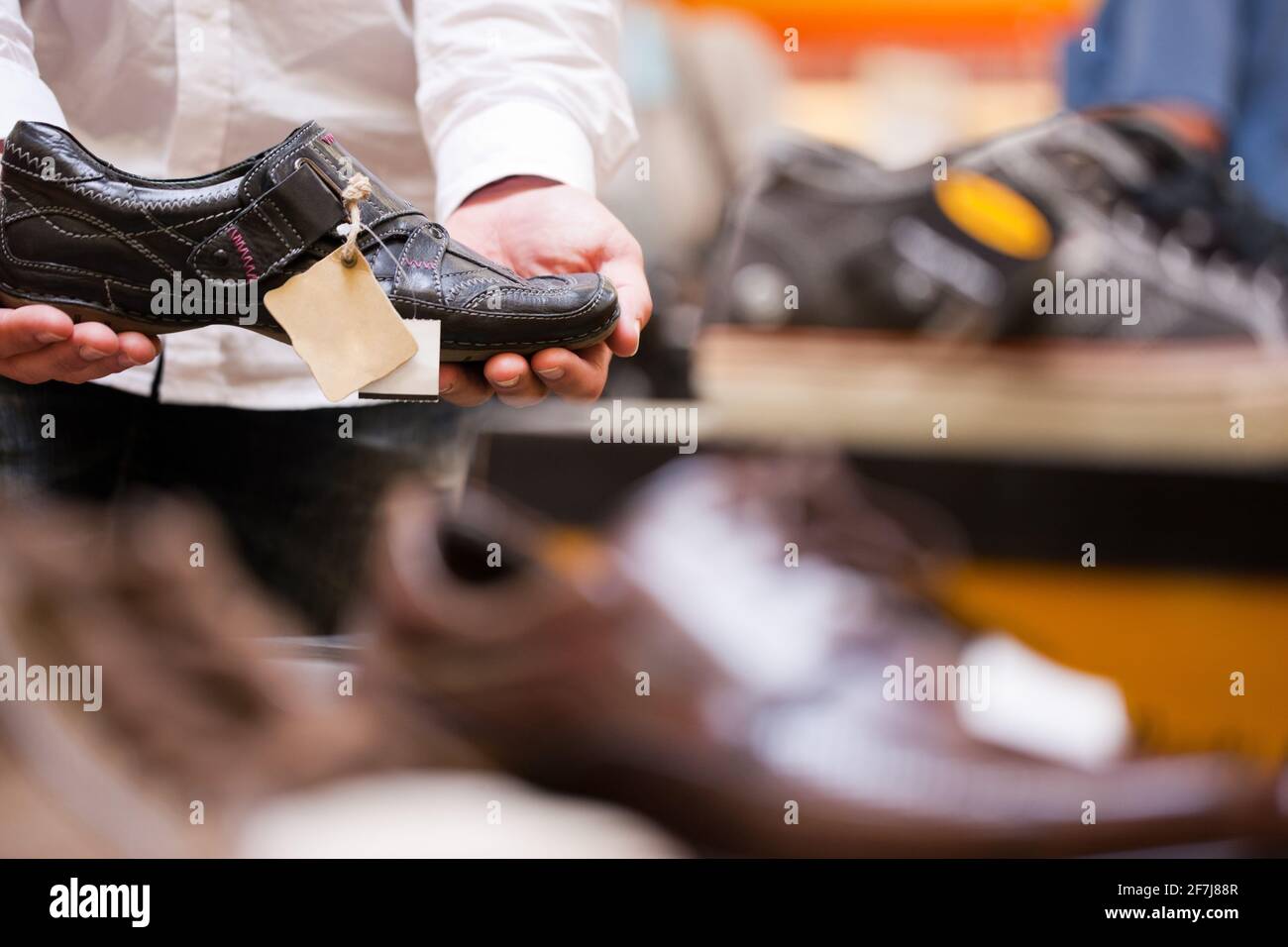 Customer holding stylish shoe at footwear department in supermarket ...