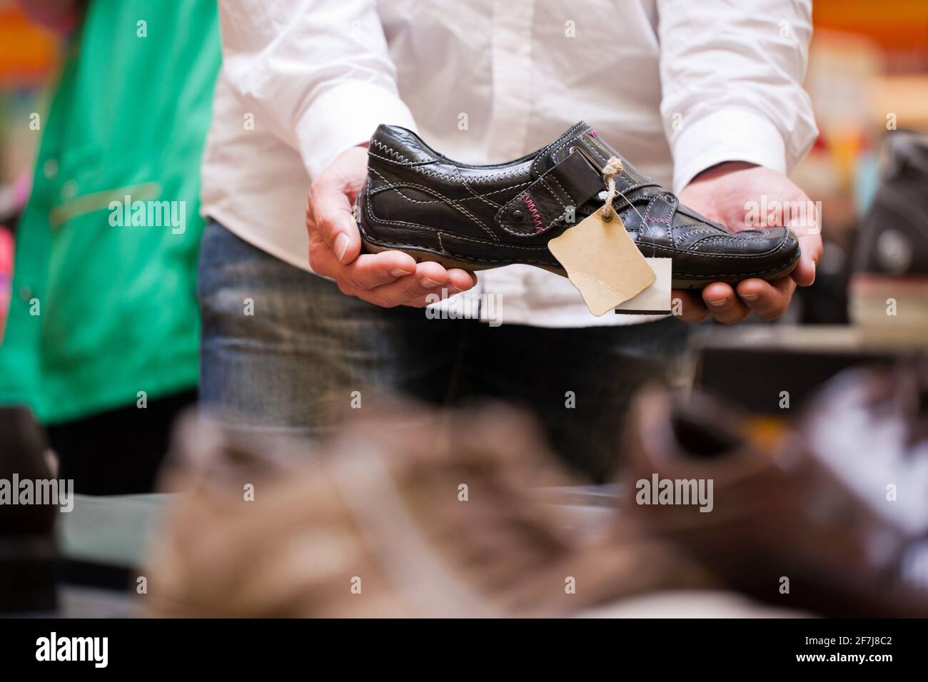 Male customer holding trendy shoe with price tag hanging Stock Photo ...