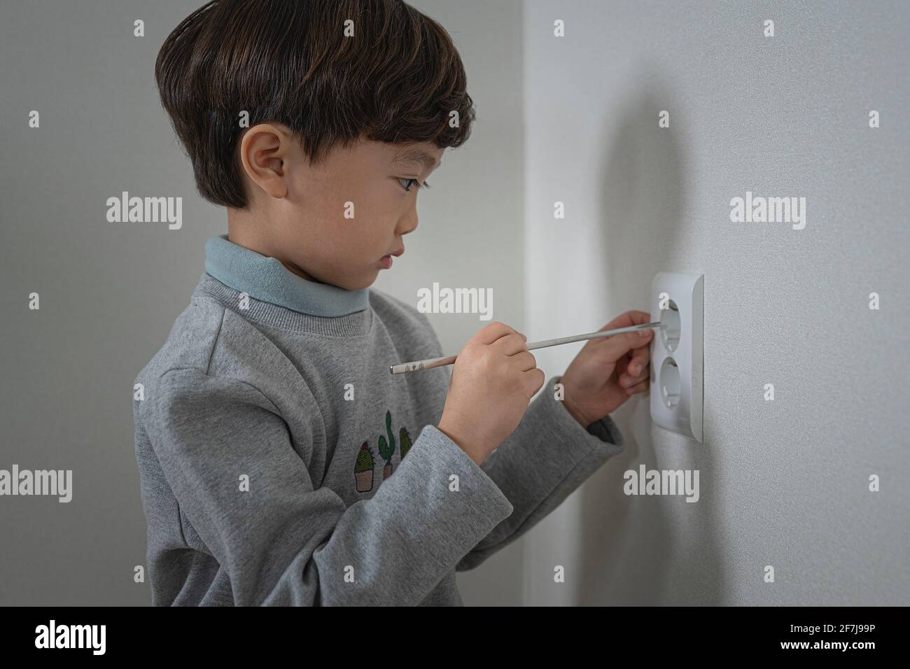 Asian boy inserting finger into an electrical outlet Stock Photo - Alamy