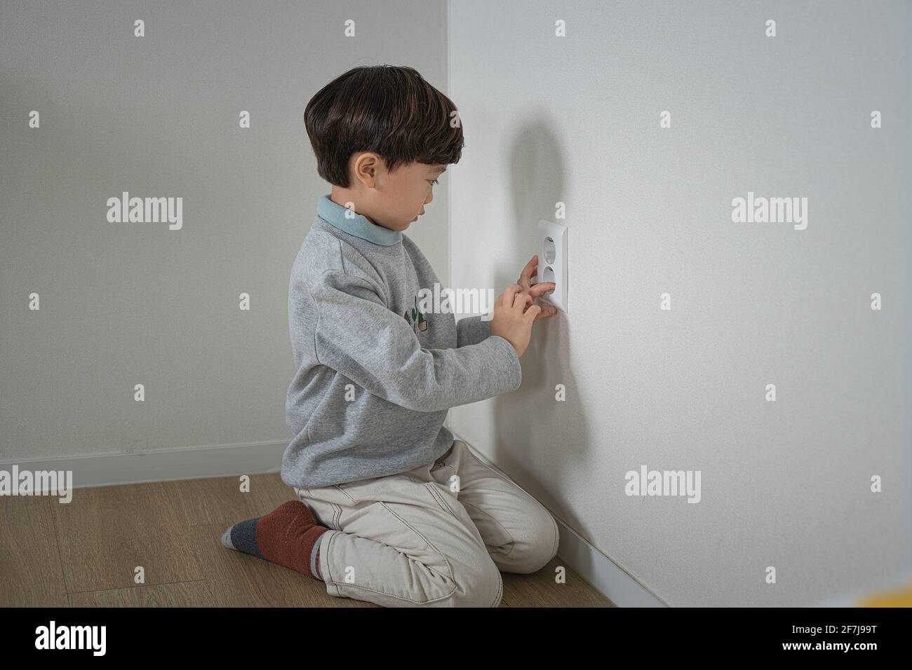 Asian boy inserting finger into an electrical outlet Stock Photo - Alamy