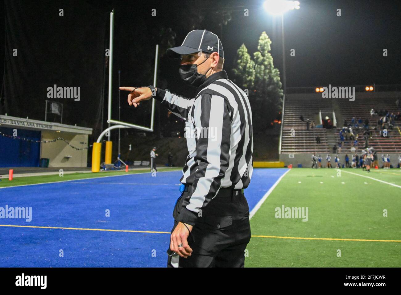 A high school football referee wears a facial covering during a high ...