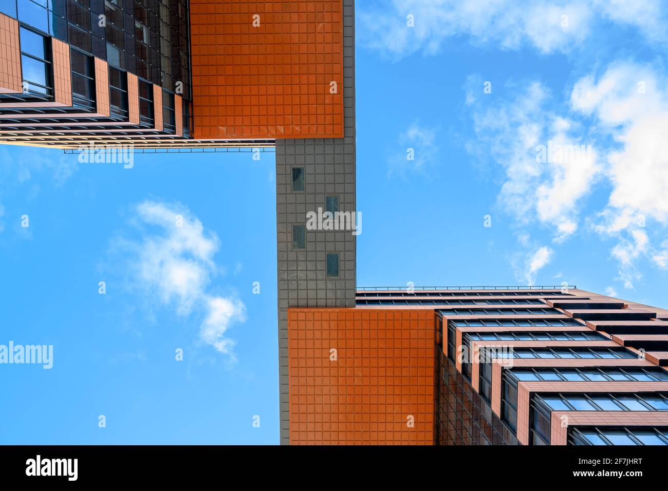 A view from below of tall office building towers connected at the top ...