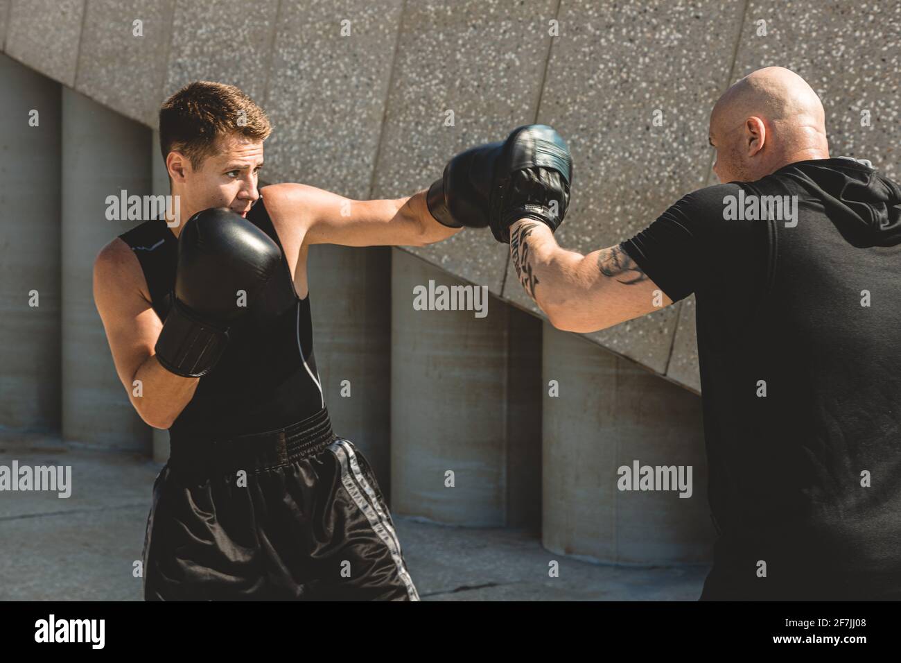 Two men exercising and fighting in outside. Boxer in gloves is training ...
