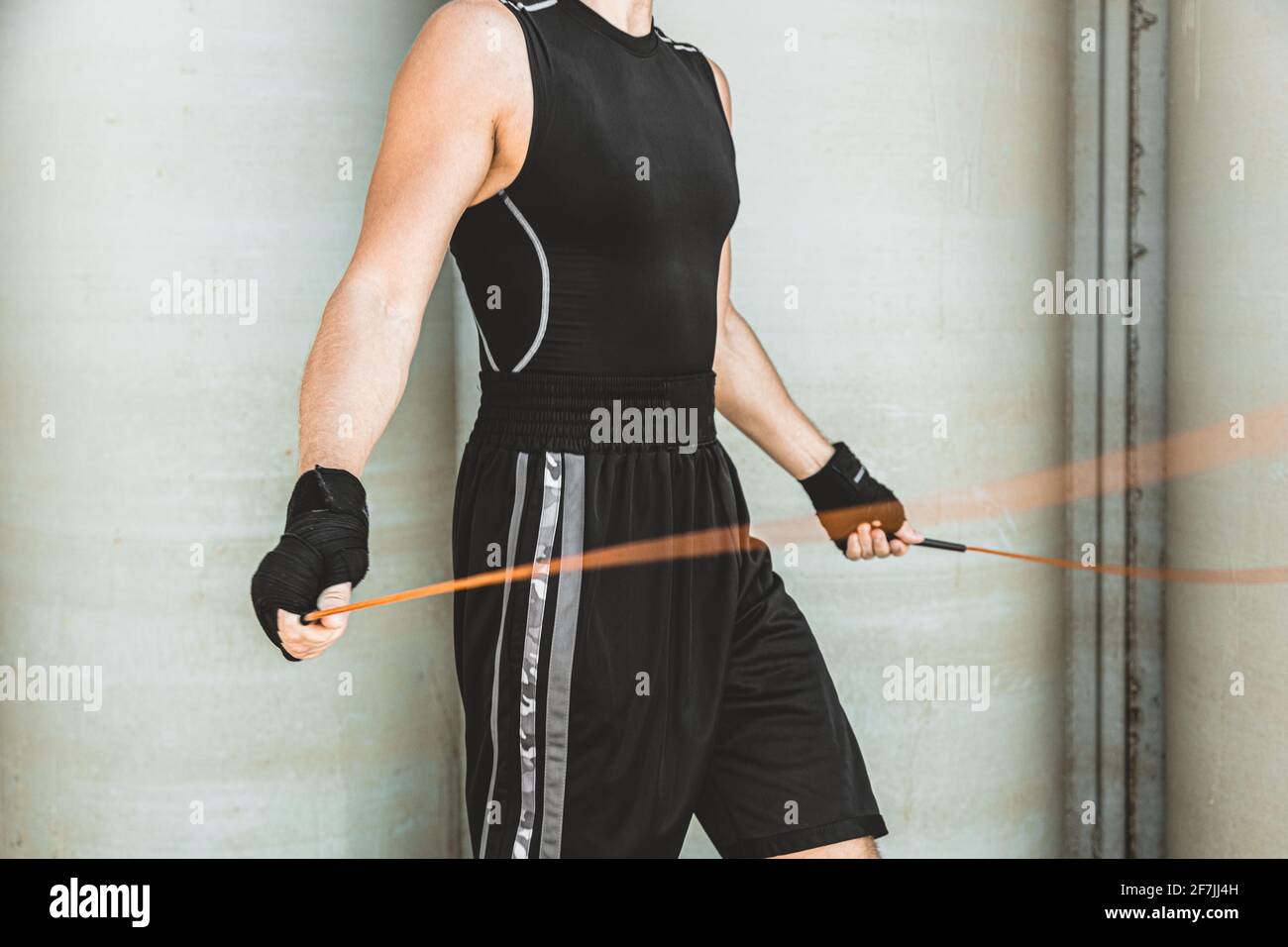 Caucasian man fighter training hard in the outdoors.. Man using rope ...