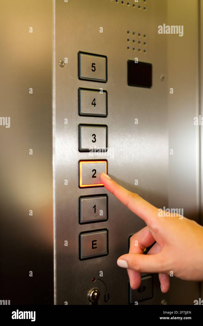 Woman in elevator or lift is pressing the button to get into the right ...