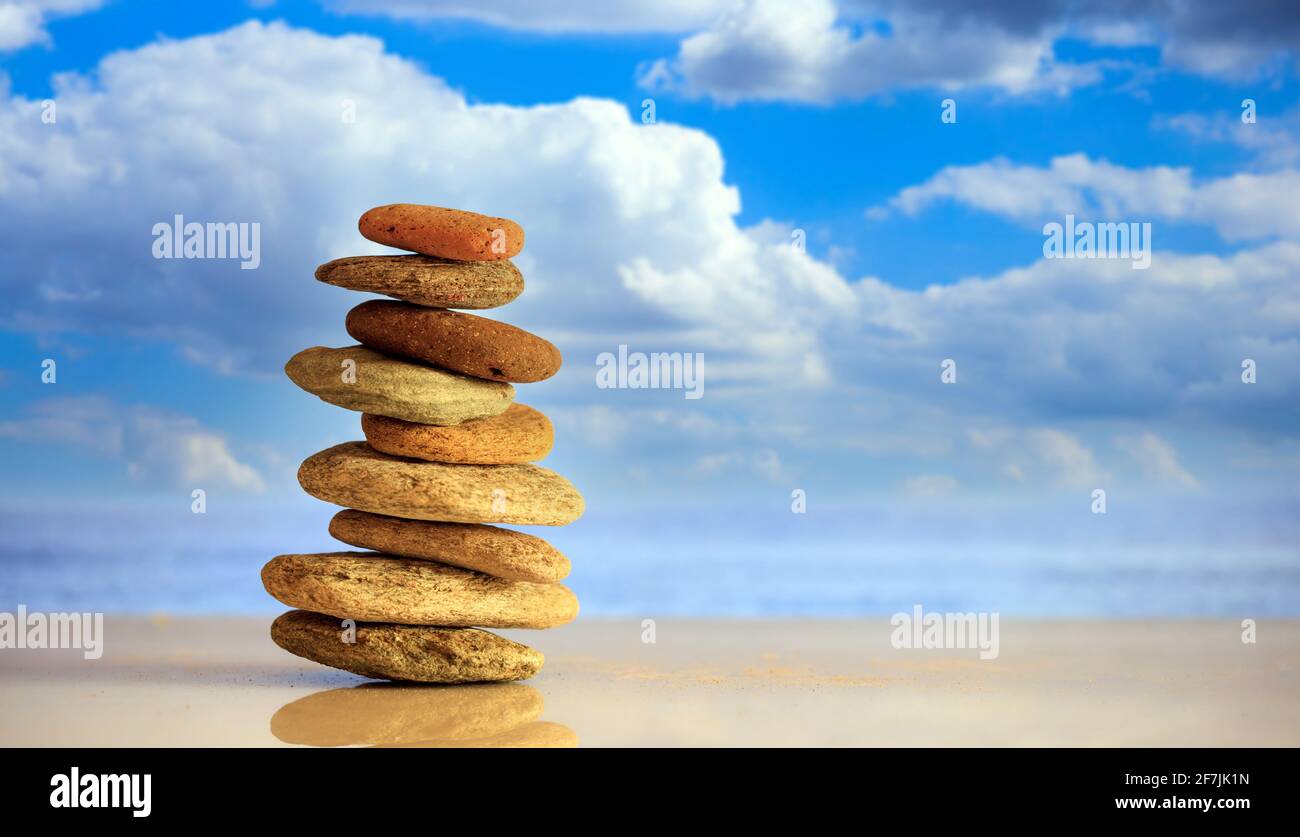 Zen stones stacked on blue cloudy sky, sea water, beach for background ...