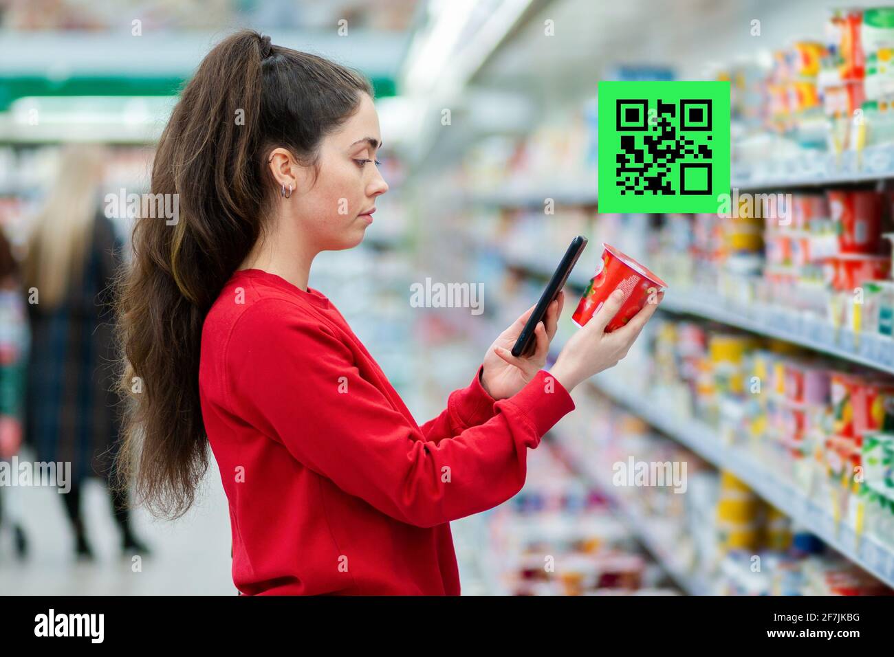A young woman scans the QR code on a package of yogurt. A picture with ...