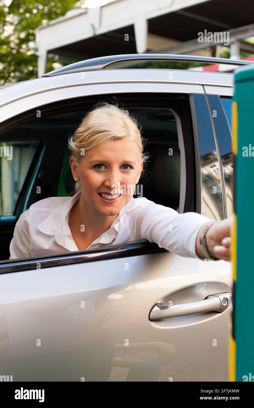 Woman is driving into a parking garage and is inserting the ticket into ...