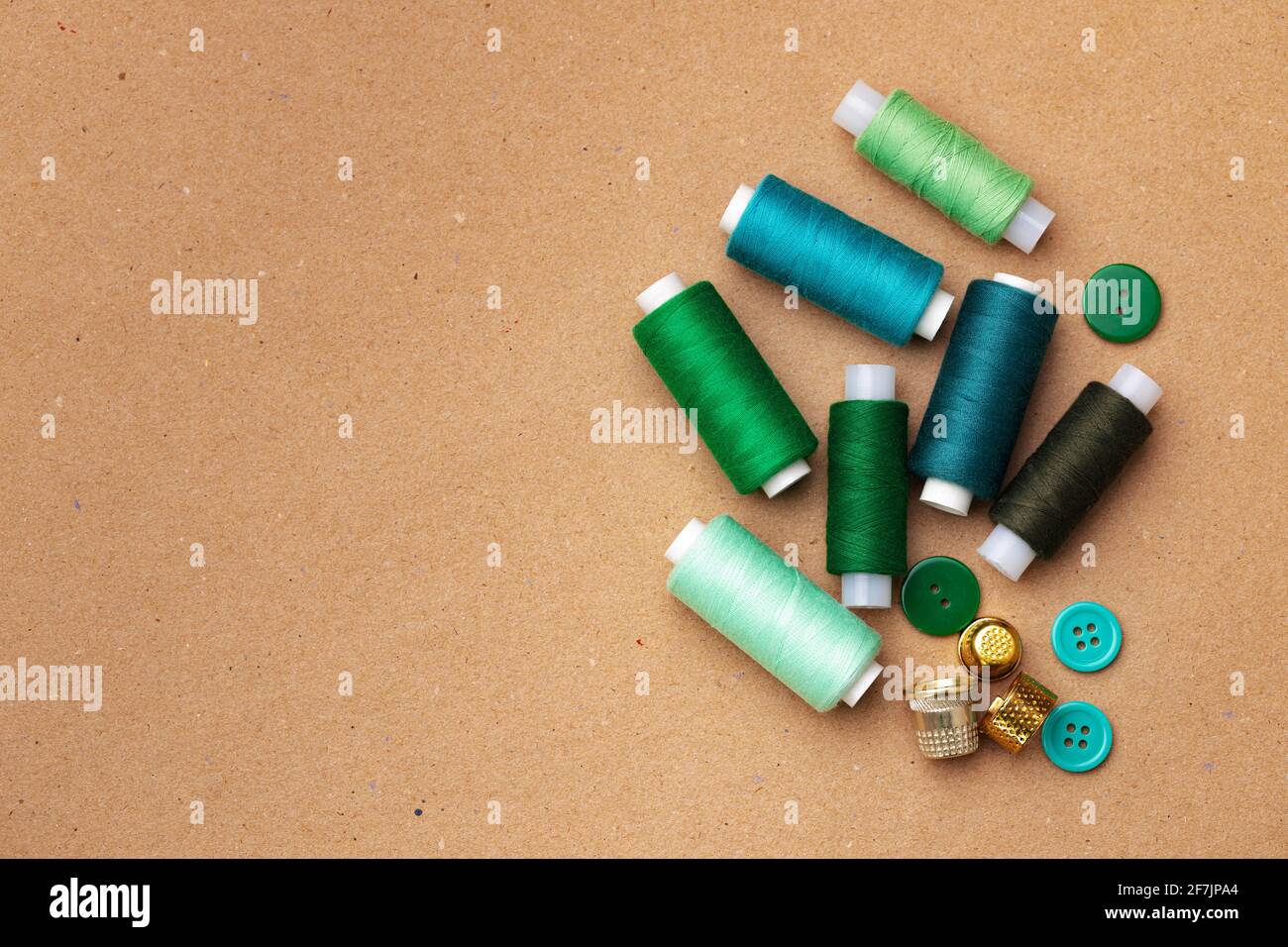 Thread spools and buttons on beige background Stock Photo - Alamy