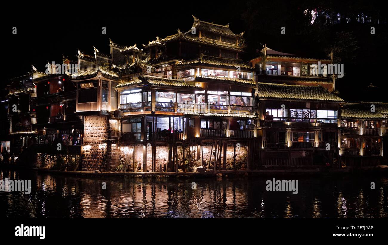 Small town with lights on and its reflaction on water Stock Photo - Alamy