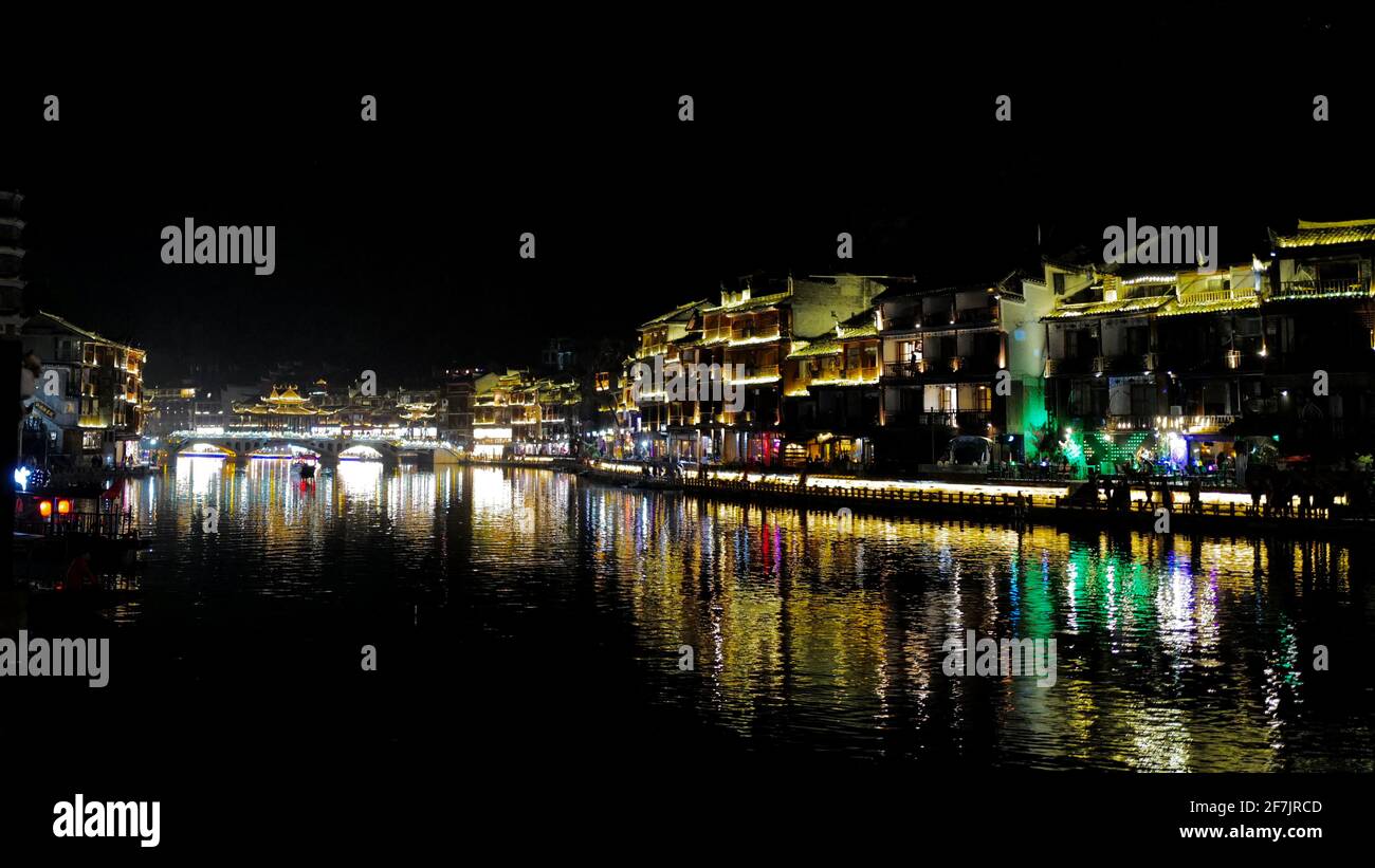Small town with lights on and its reflaction on water Stock Photo - Alamy