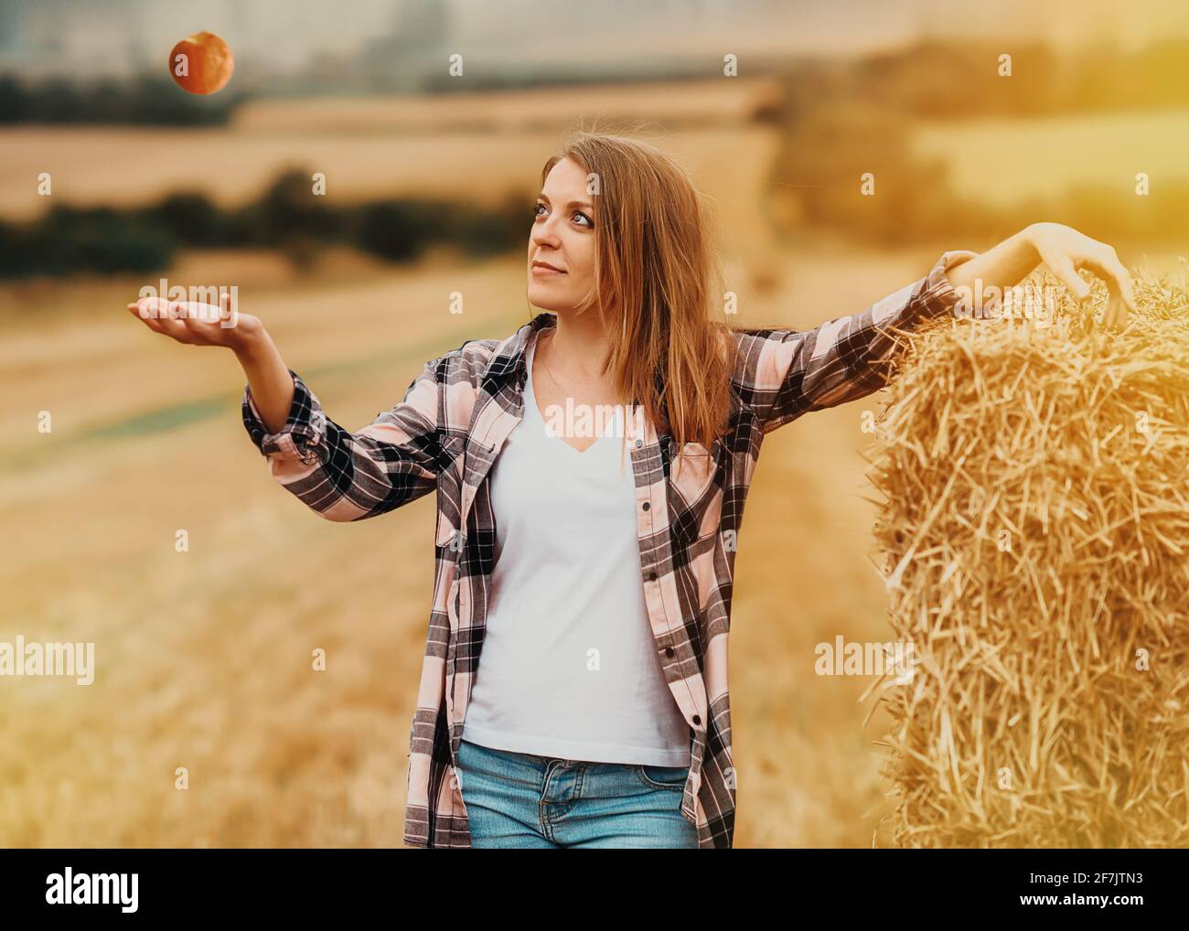 woman throwing an apple up in a wheat field Stock Photo - Alamy