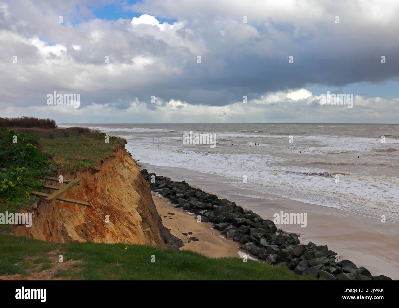 A view from eroding cliffs onto beach with rock breakwater and moderate ...