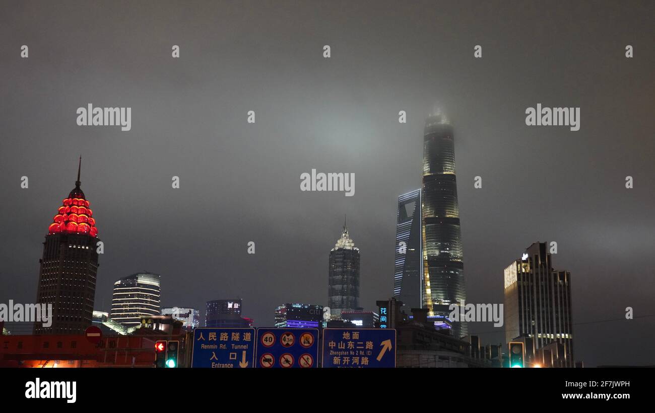 Tall buildings and towers with lights on during cloudy night in ...